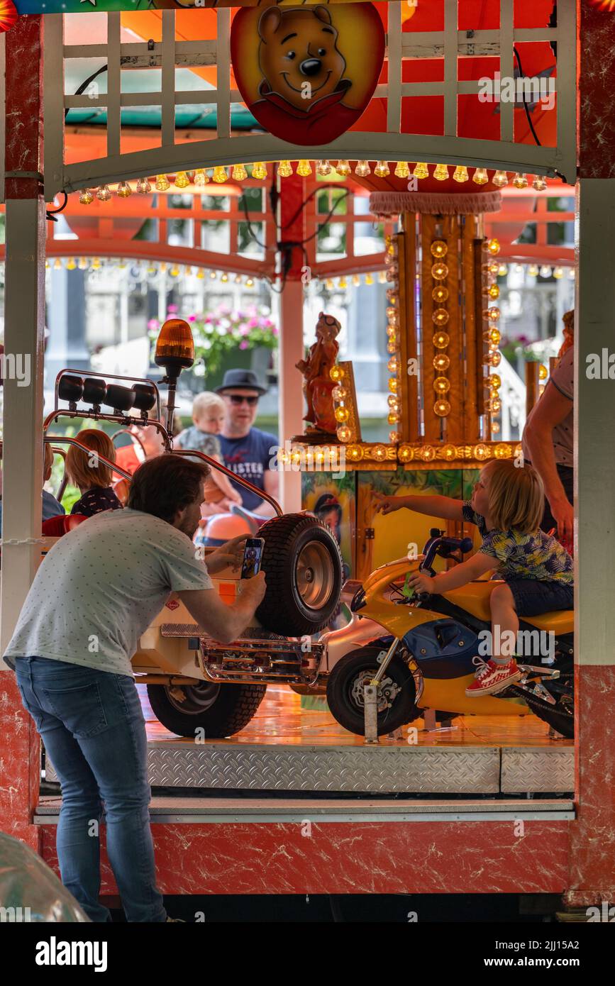A vertical shot of a father taking photos of his child riding a ...