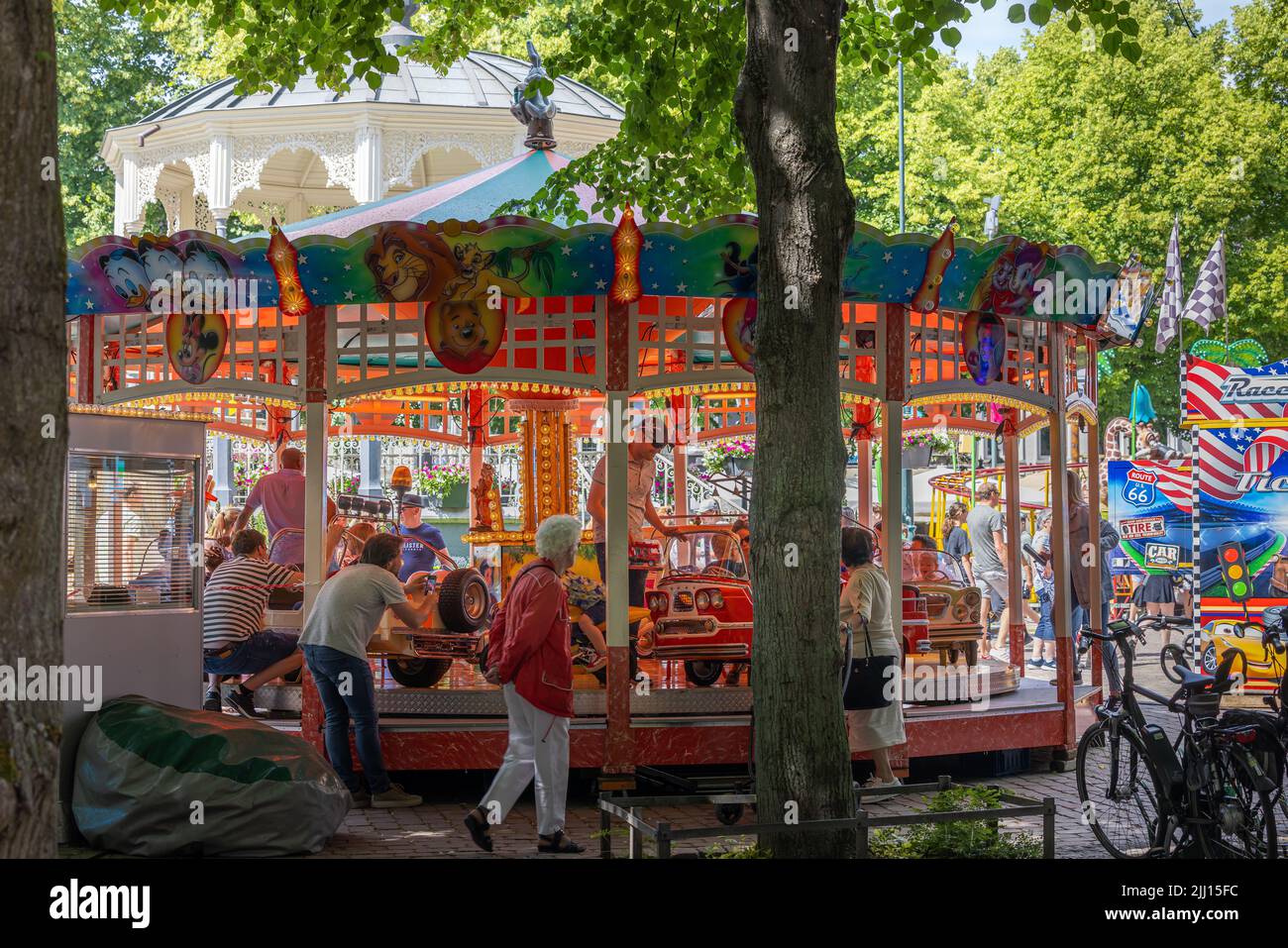 A carousel ride or merry-go-round on a fair with people enjoying ...