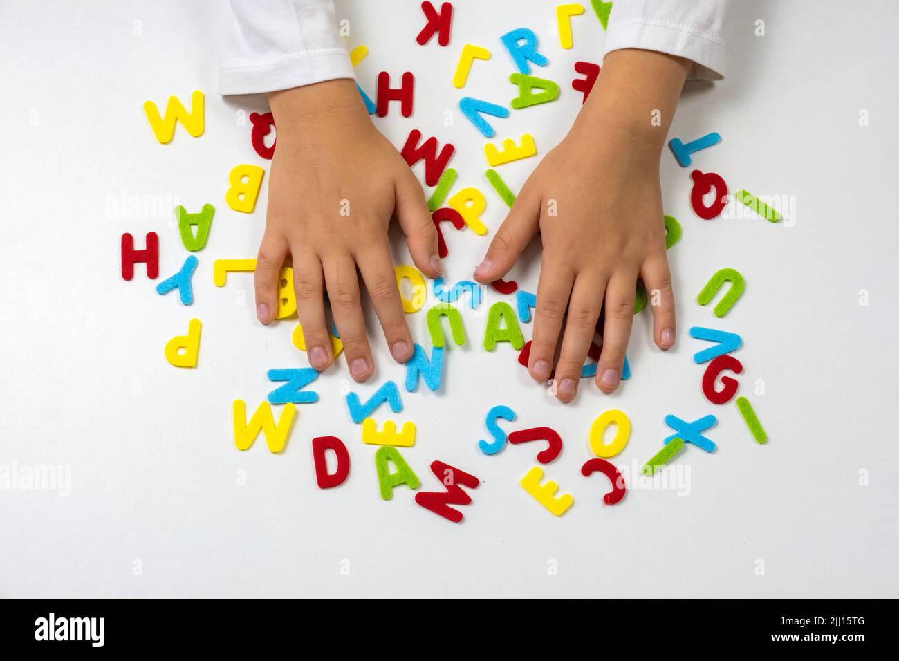 Colorful letters. The child's hands lay out colored letters on the ...
