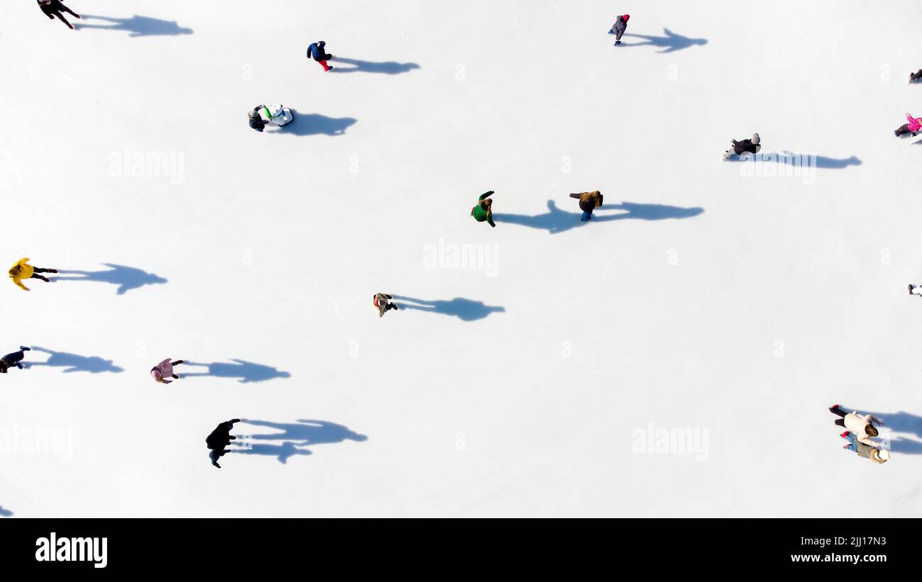 Many people are skating on a white outdoor ice rink in the city on a ...