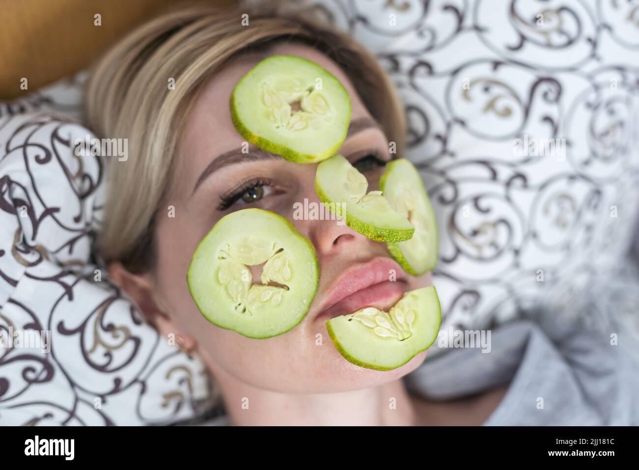 Young beautiful woman with Face pack and fresh cucumber slices on her ...