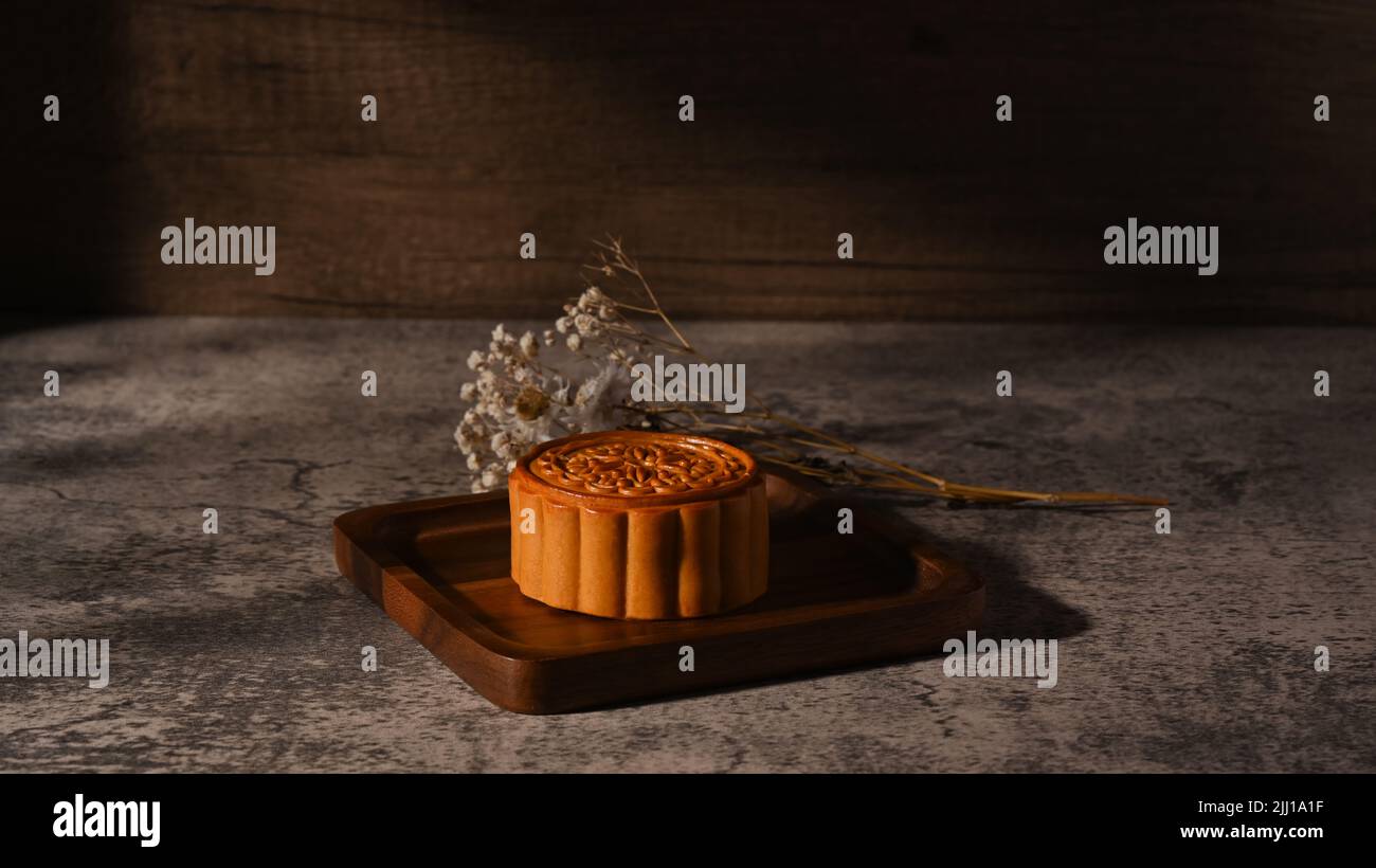 Delicious traditional mooncake on wooden tray. Mid Autumn festival and Chinese traditional ...