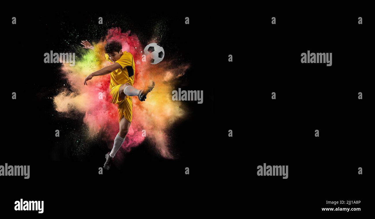 Male soccer, football player kicking ball in jump isolated on dark ...
