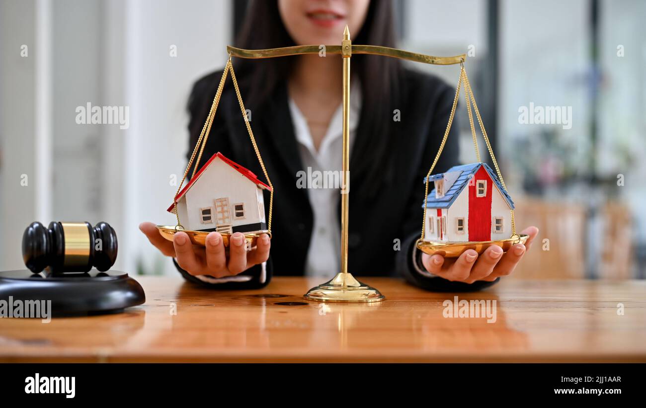 Professional Asian female lawyer protecting a house model on a scales ...