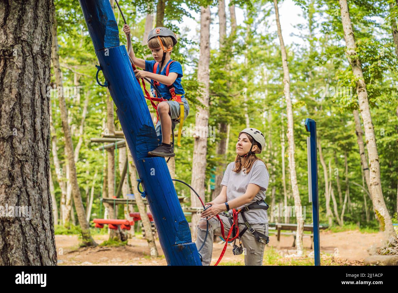 Mother and son climbing in extreme road trolley zipline in forest on ...