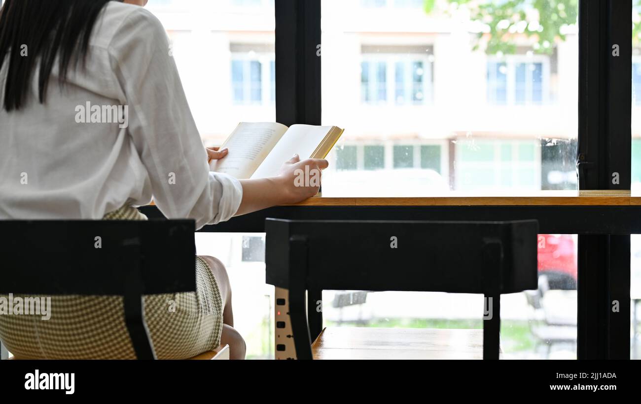 Attractive young Asian woman relaxes reading a book and sitting in the ...