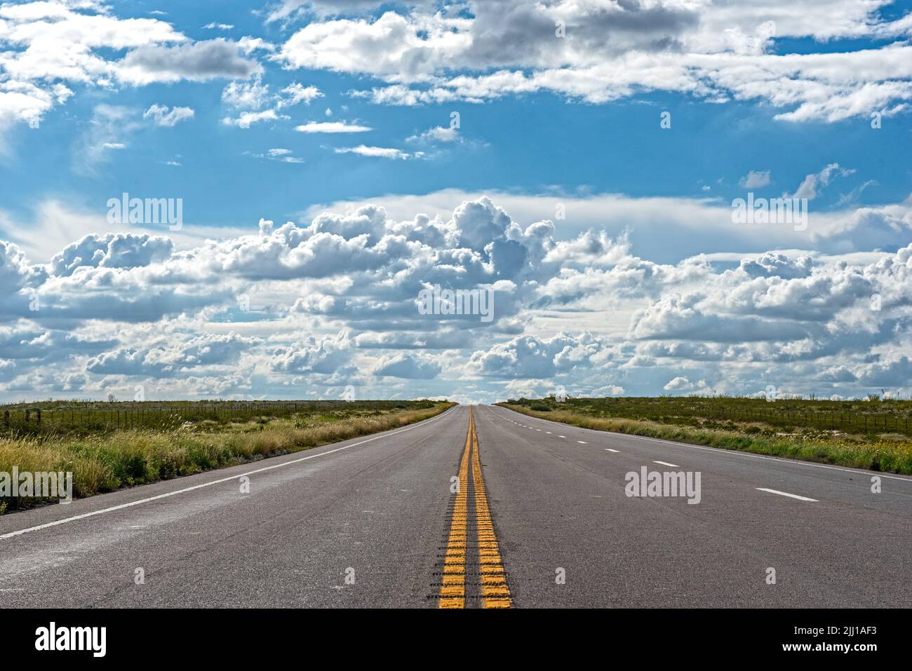 A vanishing point shot of an asphalted countryside road under a cloudy ...