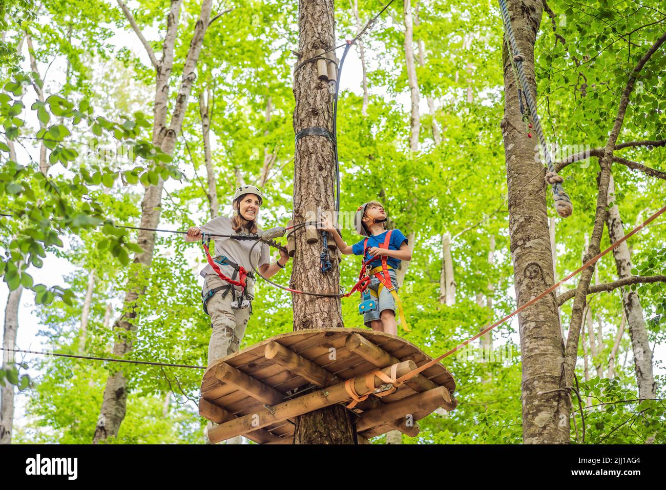 Mother and son climbing in extreme road trolley zipline in forest on ...