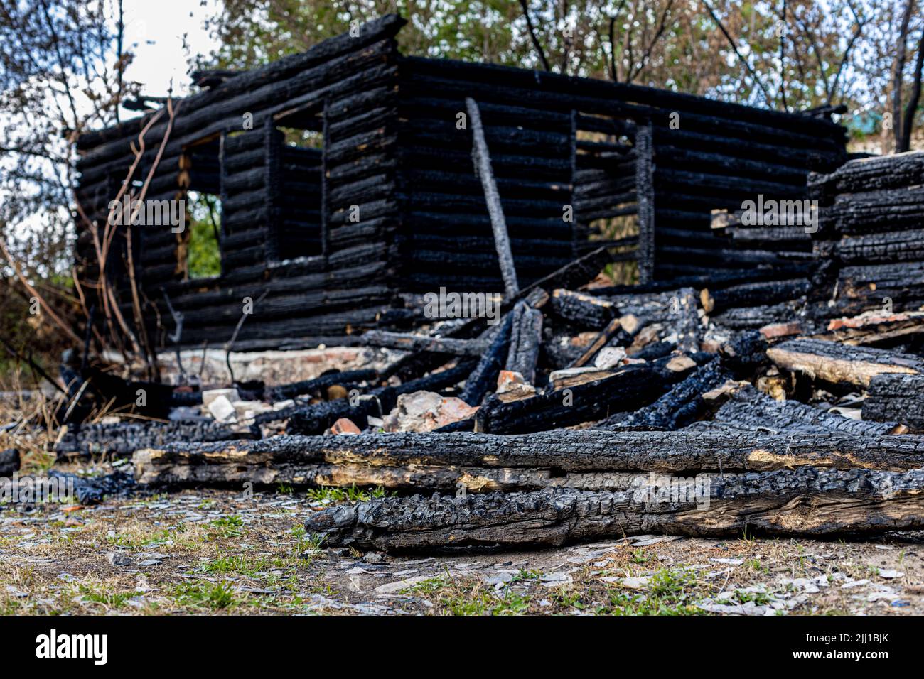 the remains of a burnt log house on the background of nature. High ...