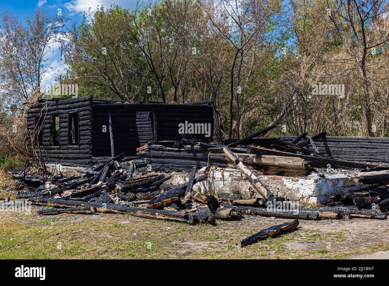 the remains of a burnt log house on the background of nature. High ...
