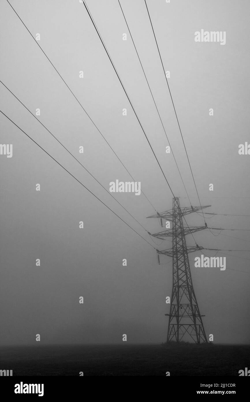 An electricity transmission tower in fog in a field Stock Photo - Alamy