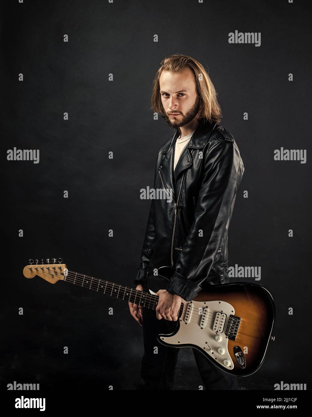 bearded rock musician playing electric guitar in leather jacket ...