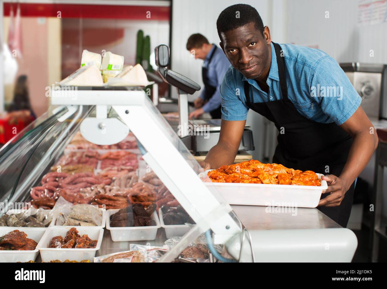 Skillful butcher with colleague working behind counter Stock Photo - Alamy