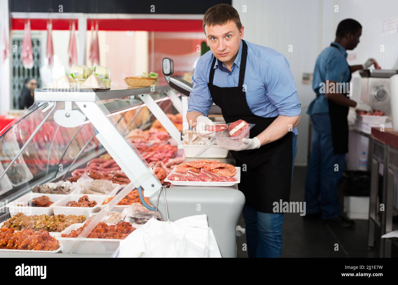 butcher arranging meat products in display case Stock Photo - Alamy