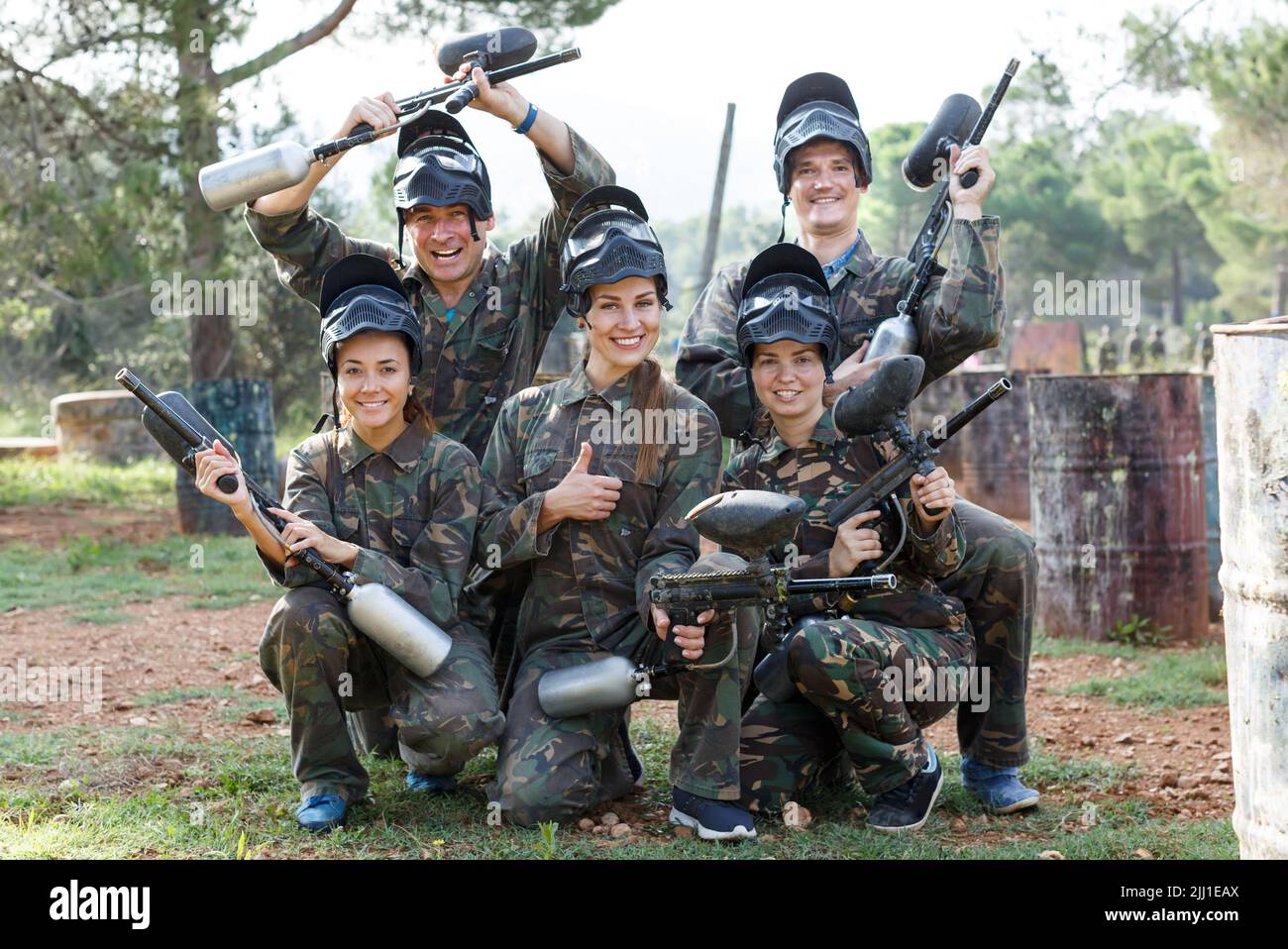 Group of excited friends paintball players in camouflage standing with ...