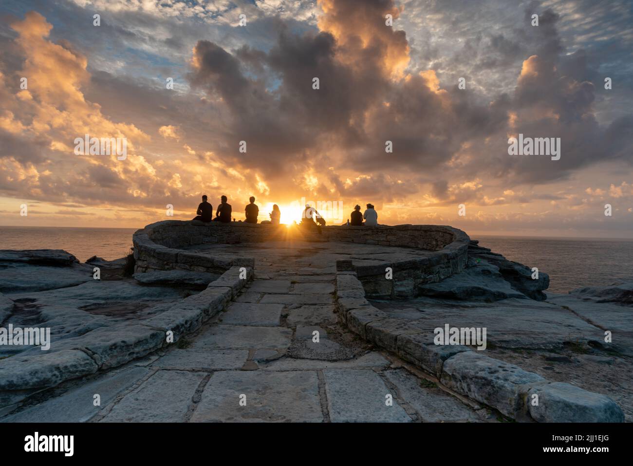 people sitting at watching the majestic sunrise at bondi rocks Stock ...
