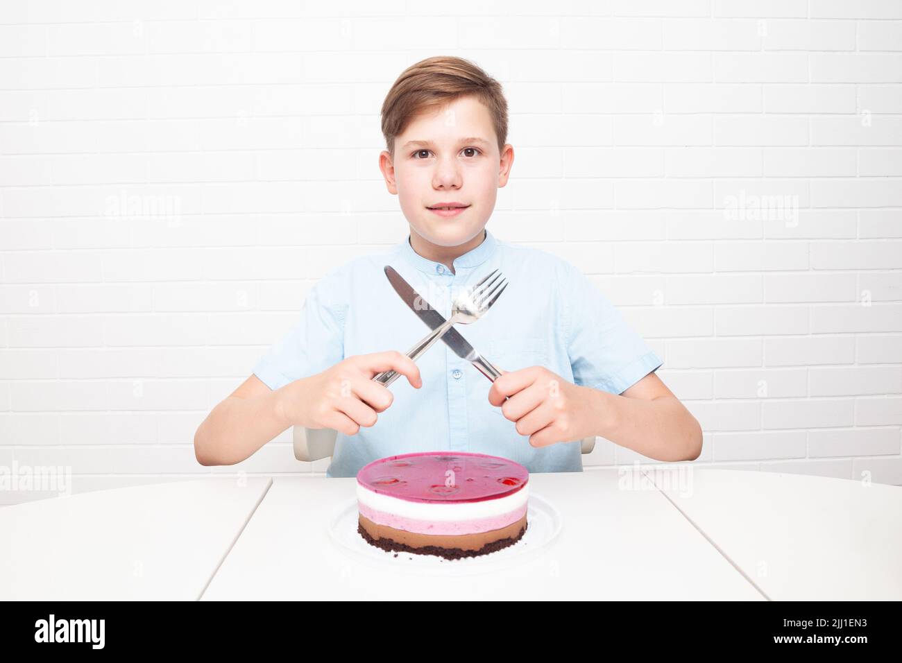 European Teenager on a white background with cutlery wants to eat a ...