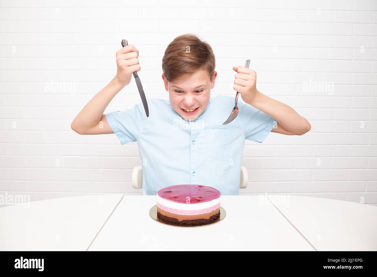 European Teenager on a white background with cutlery wants to eat a ...