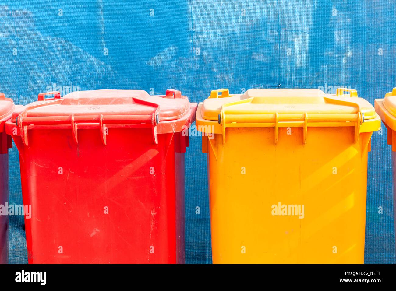 Large mobile plastic trash bins assorted colors red yellow together ...