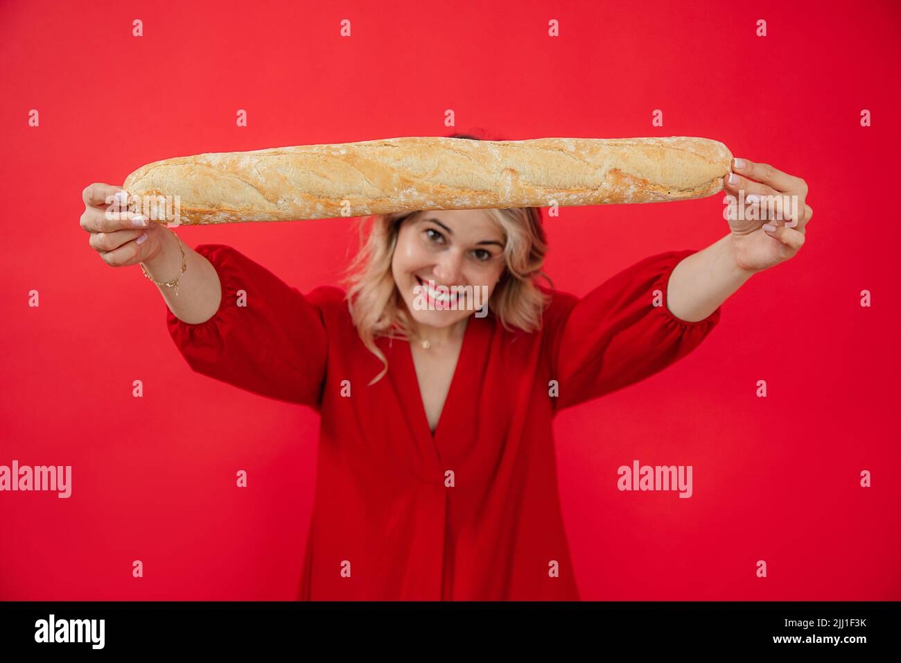 Smiling glad and joyful blonde woman in red dress holding, showing long ...
