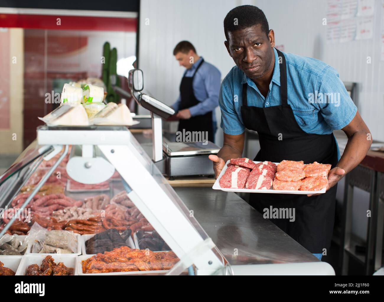Two butchers arranging meat display Stock Photo - Alamy