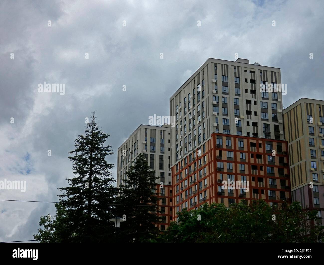 New modern block of flats in green area with blue sky. Cityscape ...