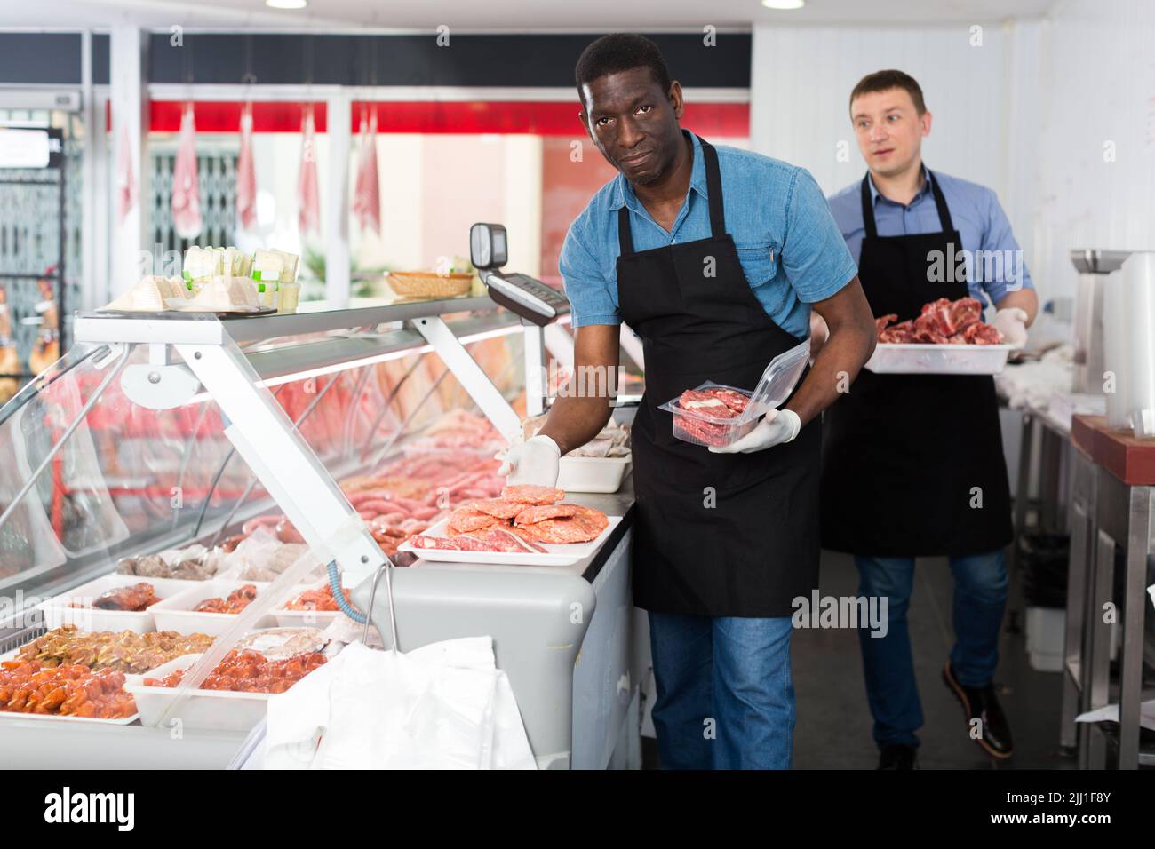 Butchers working behind counter Stock Photo - Alamy