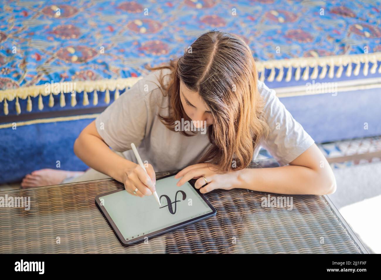 Calligrapher Young Woman writes phrase on digital tablet. Inscribing ...