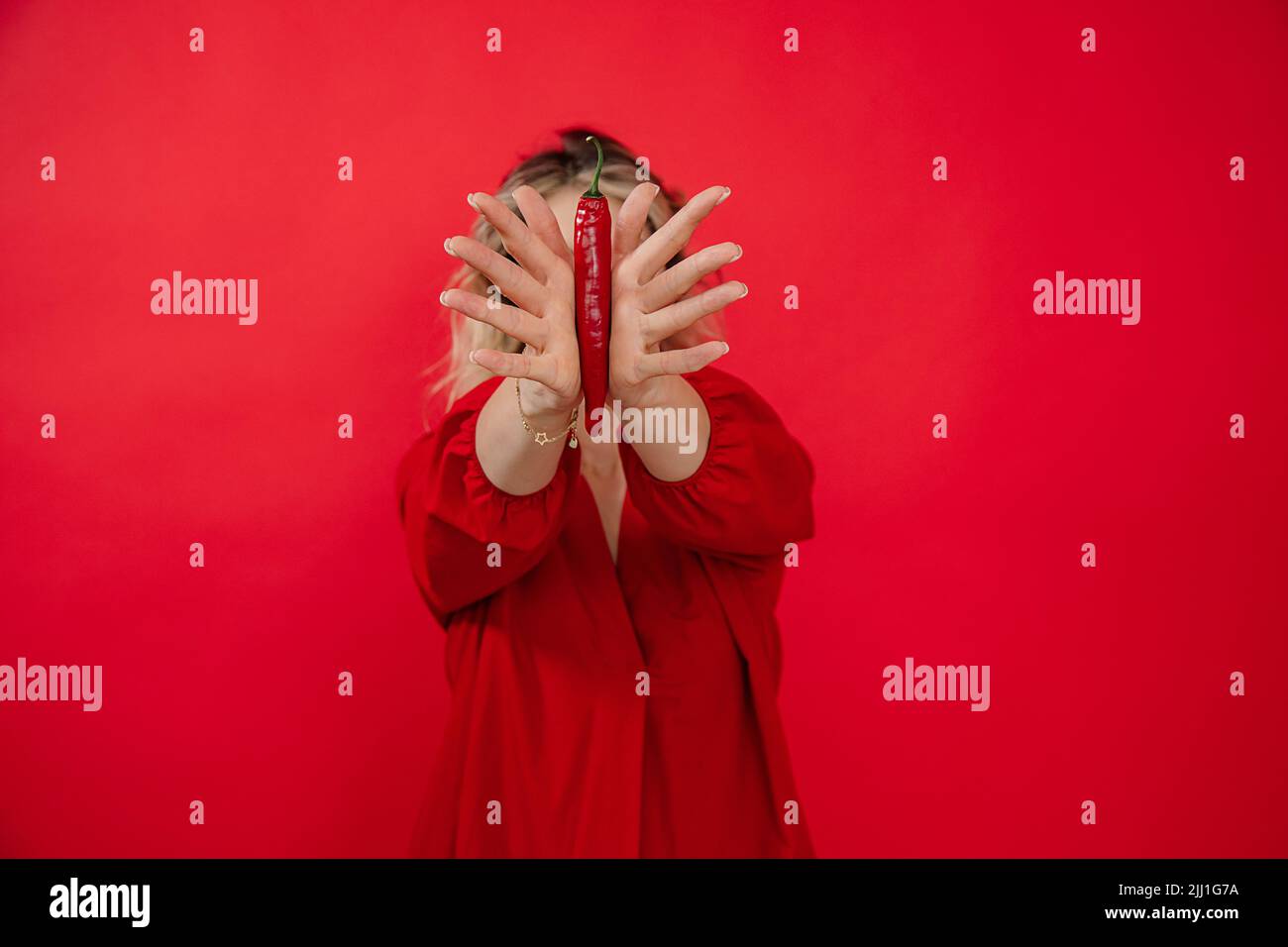 Unrecognizable woman in red outfit hold and cover face by chili pepper ...
