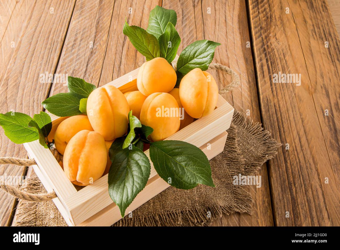 large juicy apricots in a wooden box with rope handles on a village ...
