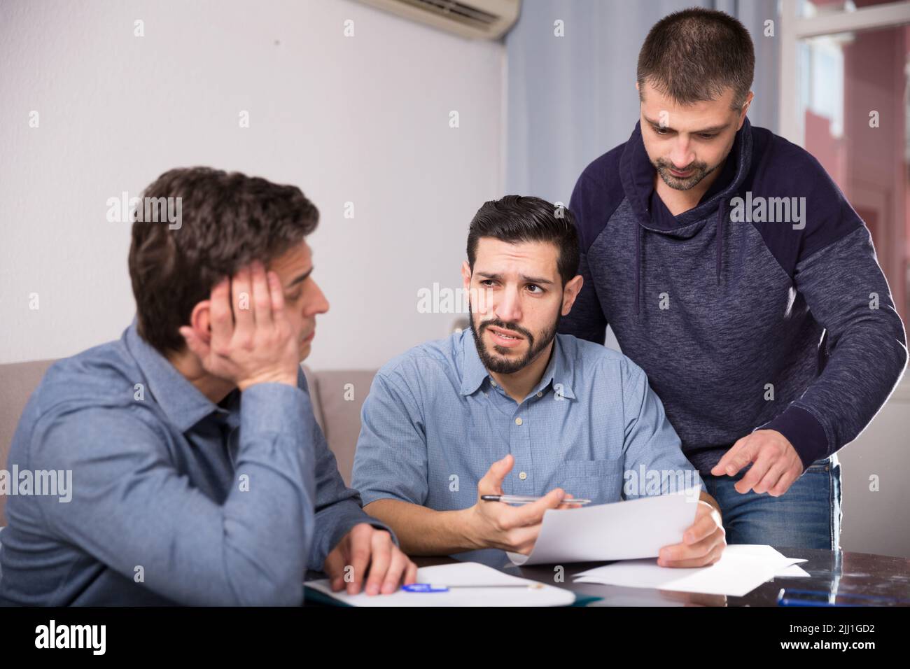 Three men worriedly discussing documents Stock Photo - Alamy