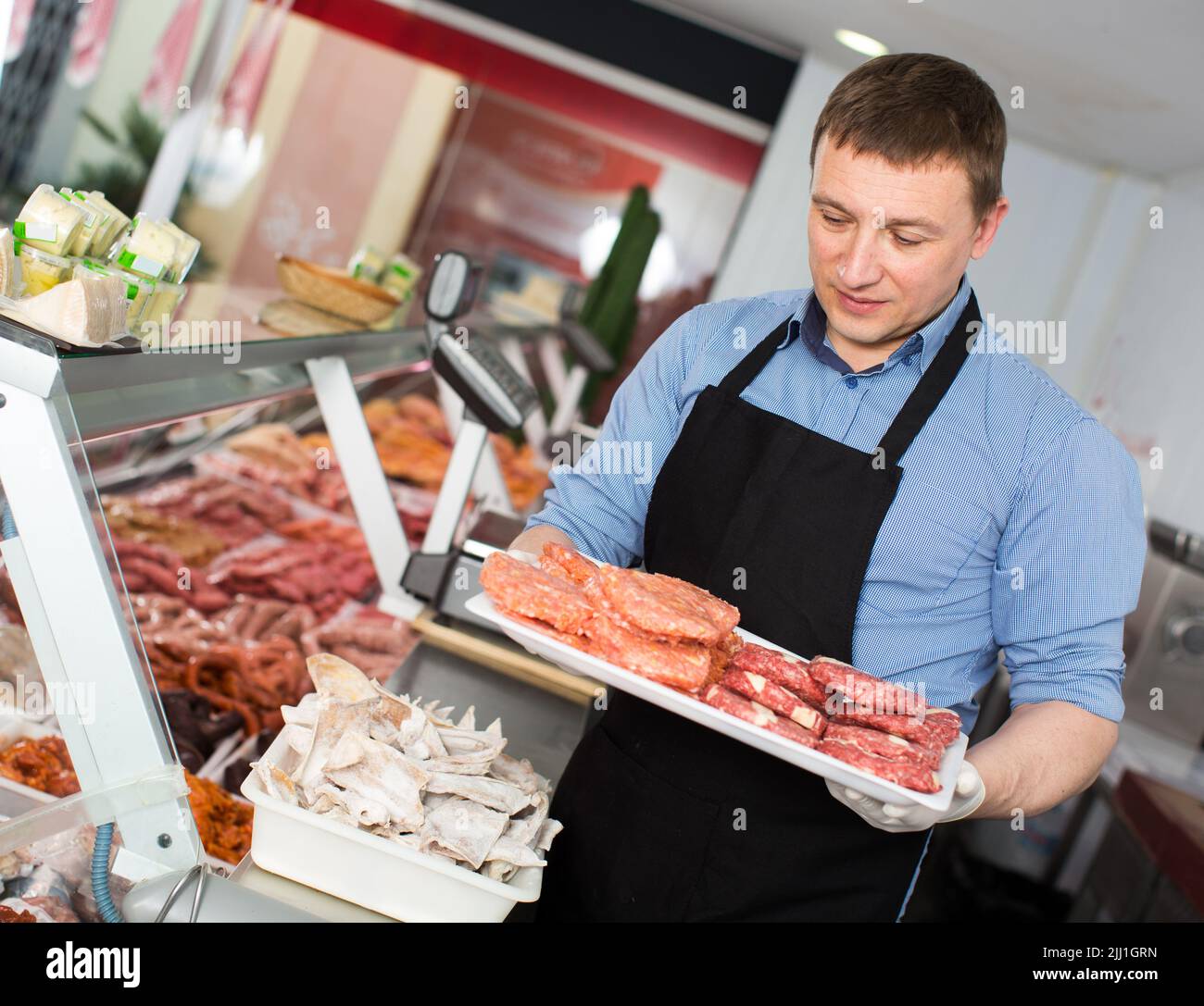 Butcher arranging meat display Stock Photo - Alamy