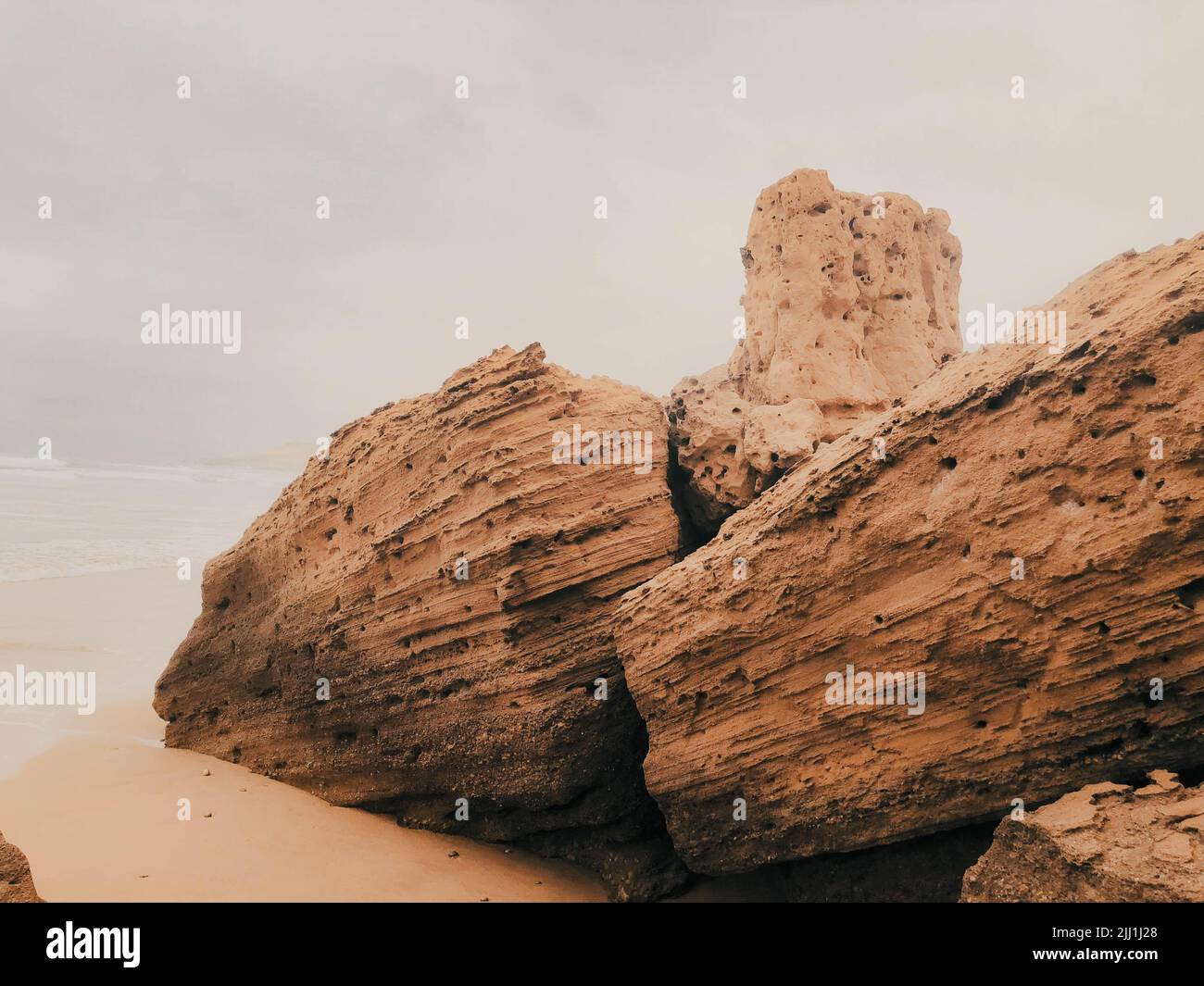Rocky cliffs on a beach over a background of a cloudy sky Stock Photo ...