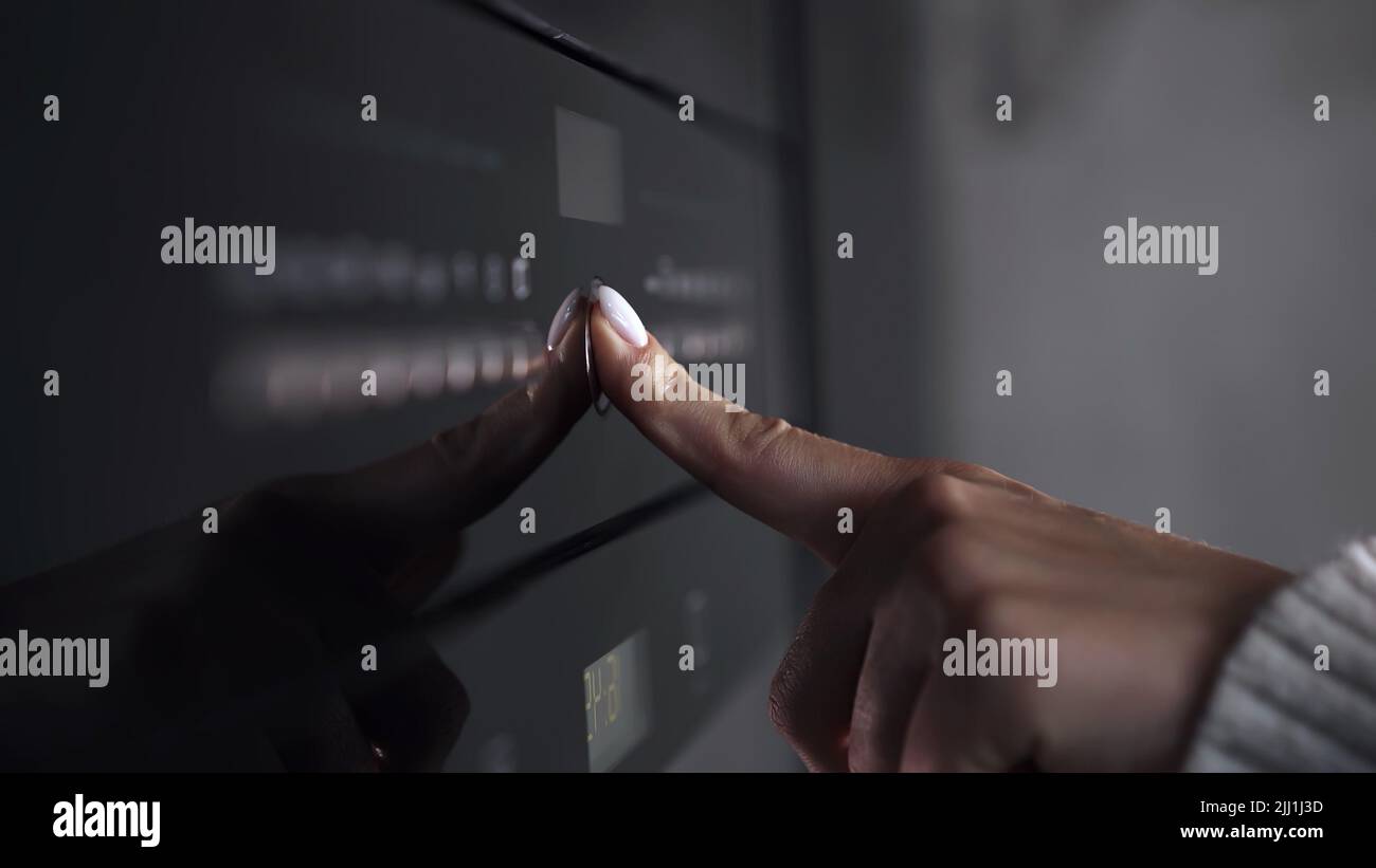 Female finger presses button on modern gas stove or oven. Woman cooking ...