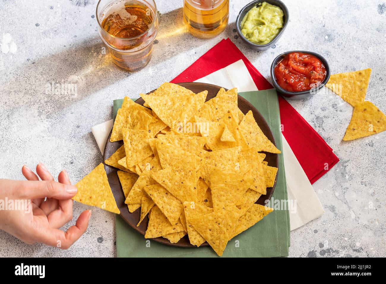 Female hand hold one of nachos, Mexican snack served with traditional ...