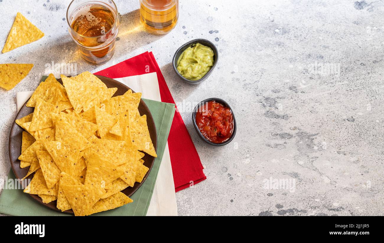 Famous Mexican snack, nachos with guacamole, red chilli sauce and beer ...