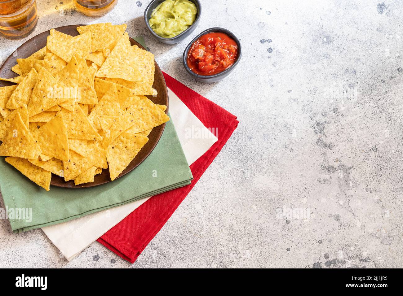 Famous Mexican snack, nachos with guacamole, red chilli sauce and beer ...