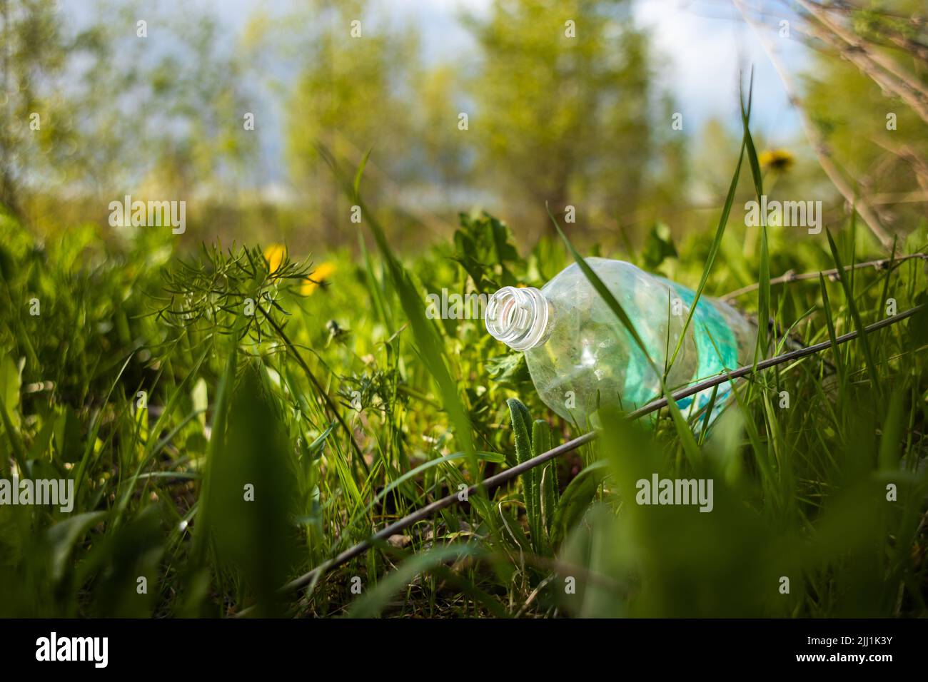 Abandoned garbage plastic and glass waste in nature among the grass ...