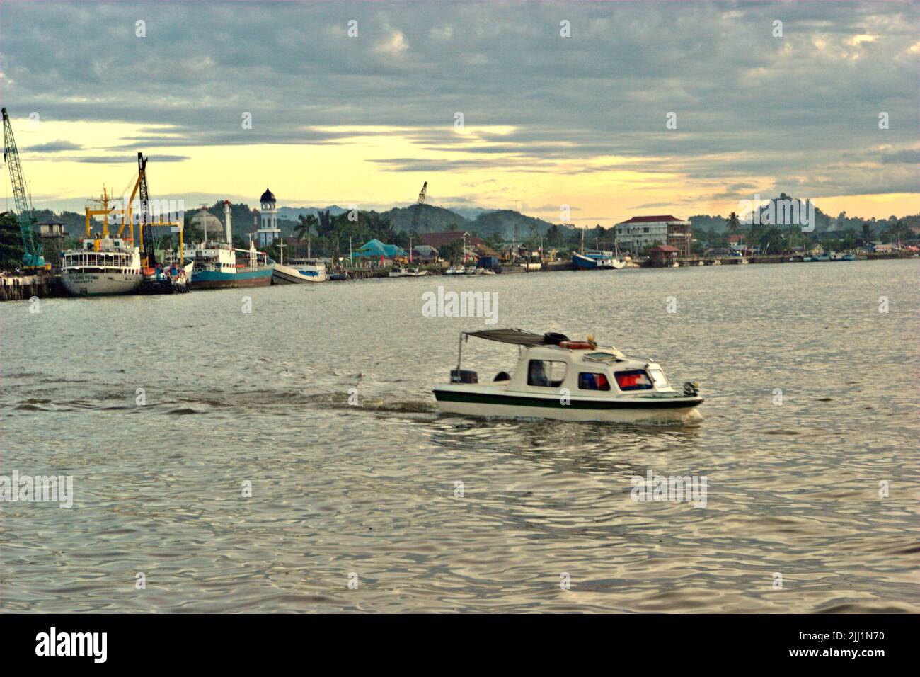 A boat sailing on Segah river, in a background of riverport and ...