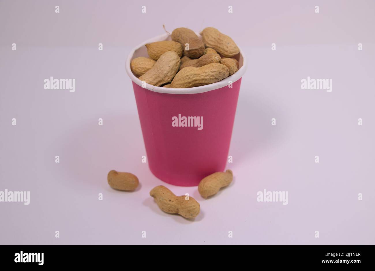 Shelled peanuts in paper cup on a white surface Stock Photo - Alamy