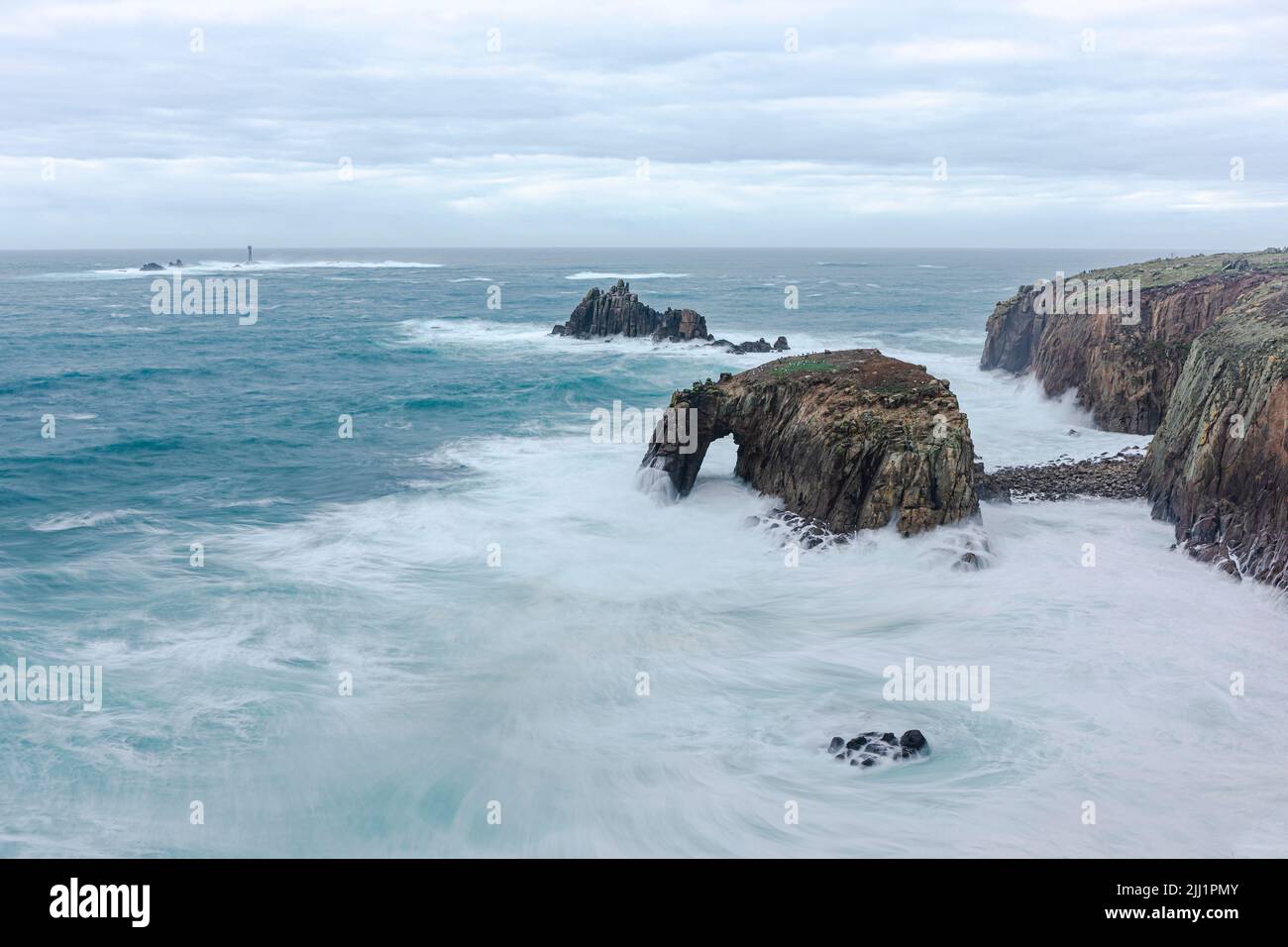 Enys Dodnan Arch at Land's End, with Longships Lighthouse in the ...
