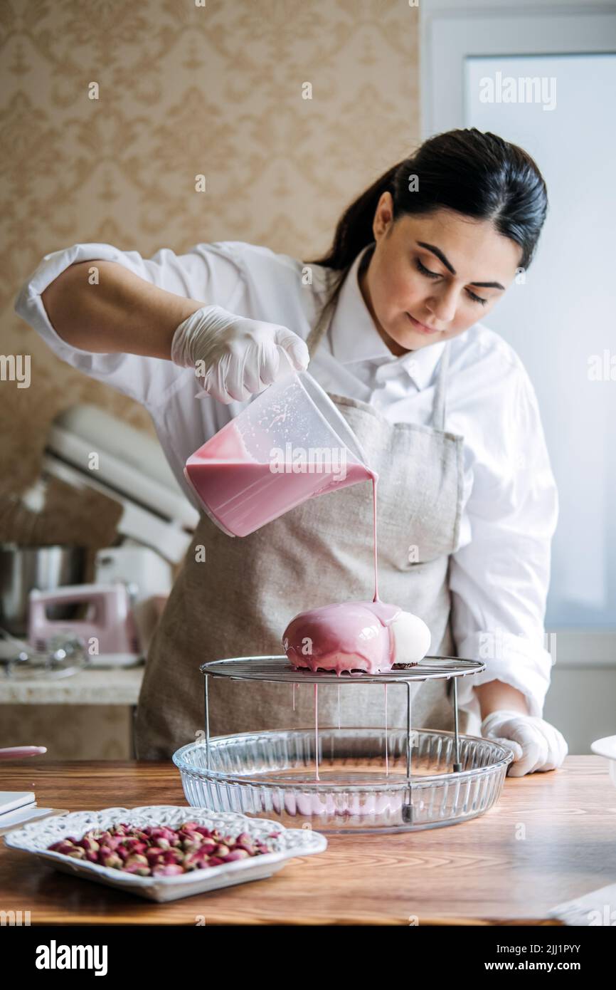 Central Asian Arabic woman pastry chef making Mirror Glaze Mousse cake ...