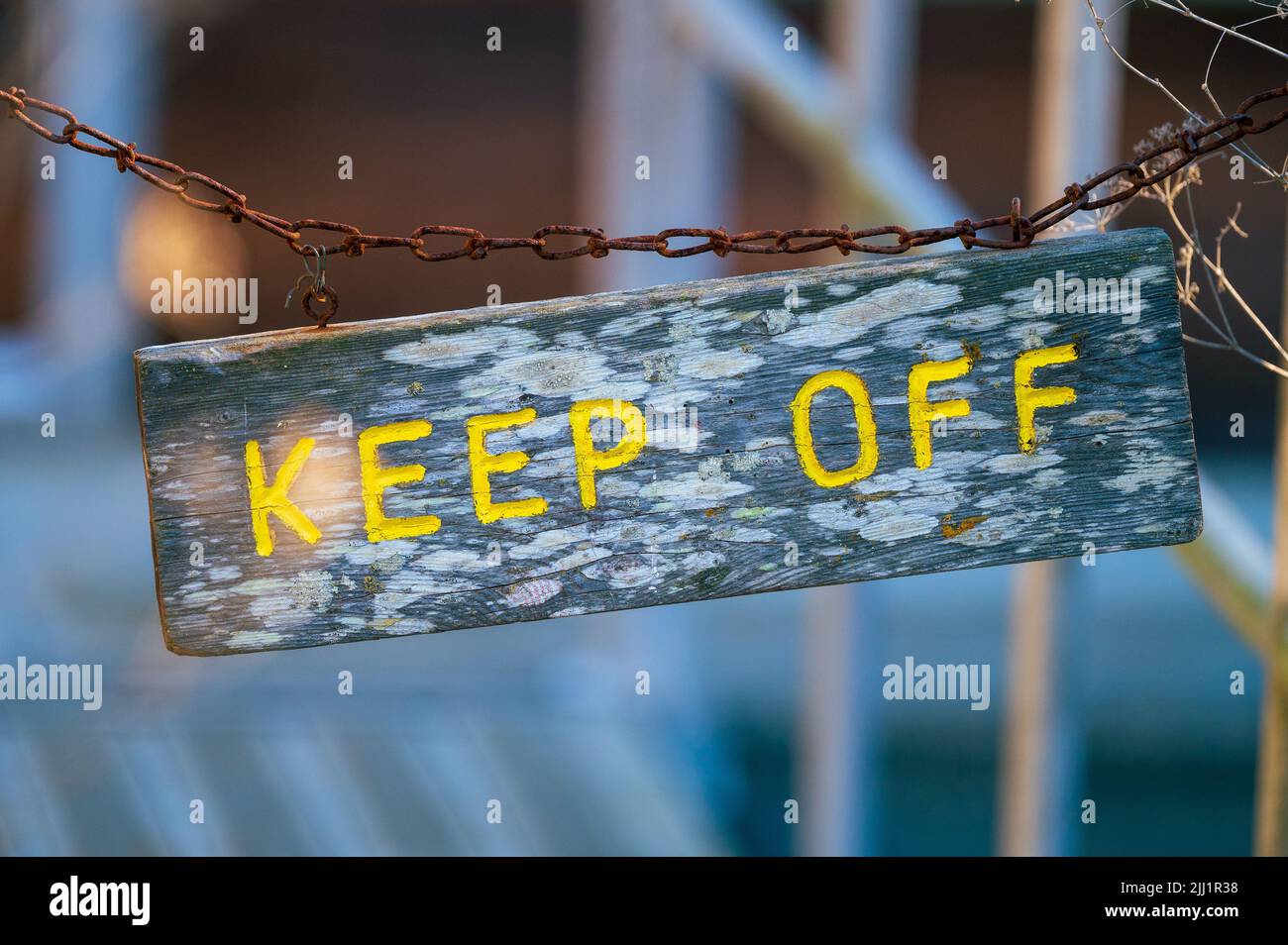 The inscription " keep off " on wooden plaque attached to a rusty metal ...