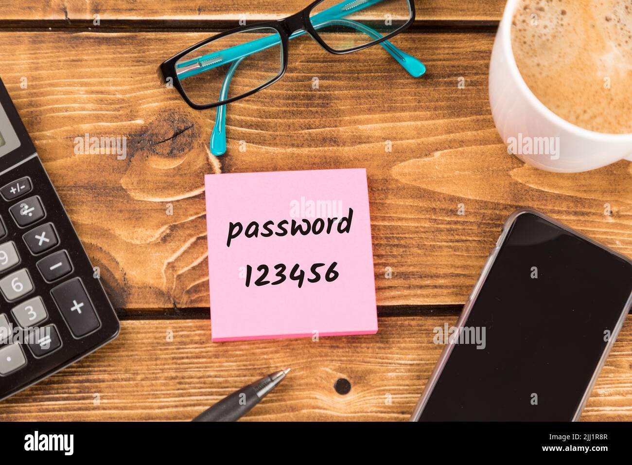 A desk with 'password 123456' text on pink paper surrounded by ...