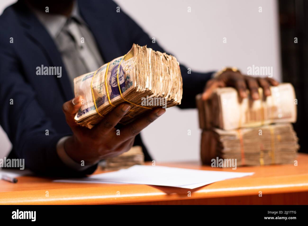 african businessman offering a bundle of cash Stock Photo - Alamy
