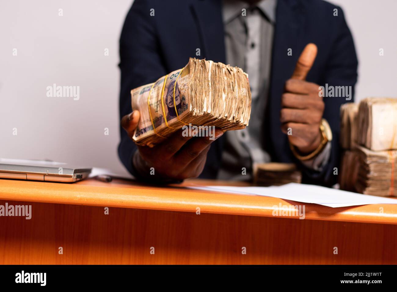 african businessman offering a bundle of cash Stock Photo - Alamy