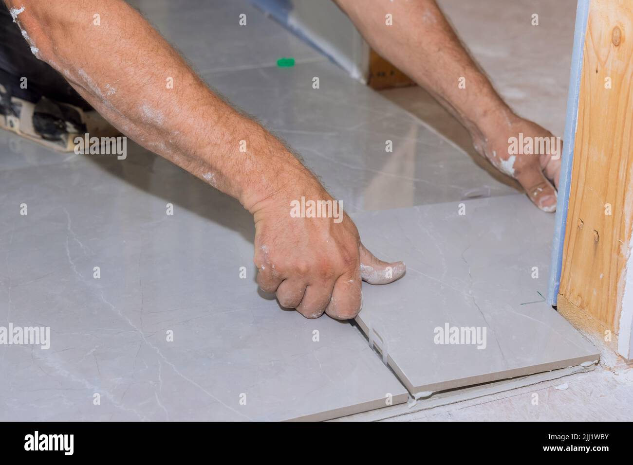 With the help of a home construction worker, placing ceramic tile on an ...