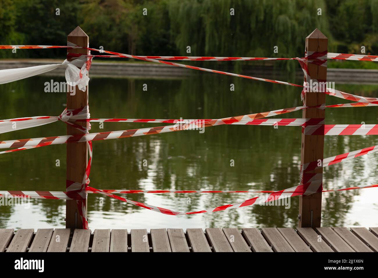 Wooden dock on the lake closed off with red and white caution tape ...