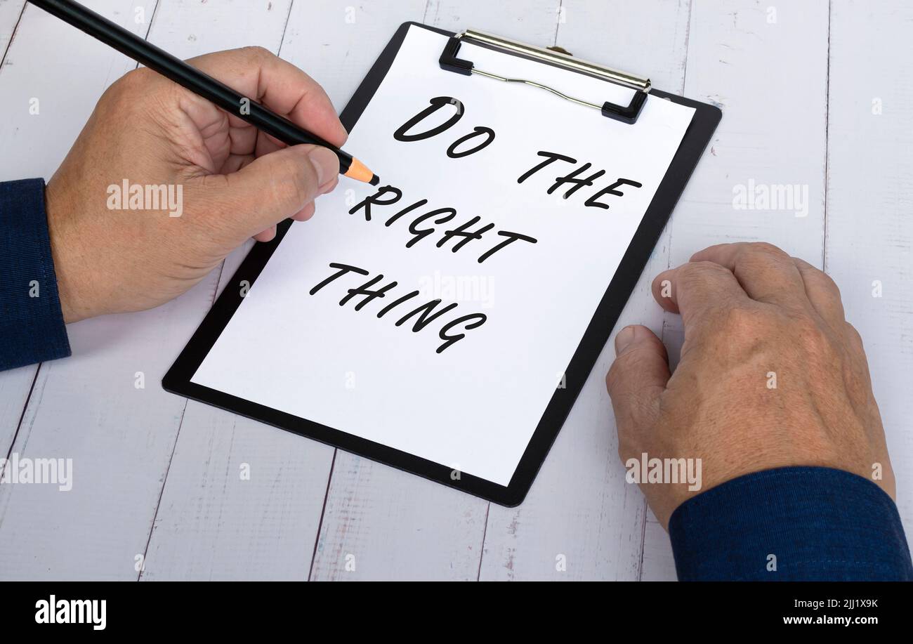 Hand with pencil writing the words Do The Right Thing on a paper with ...