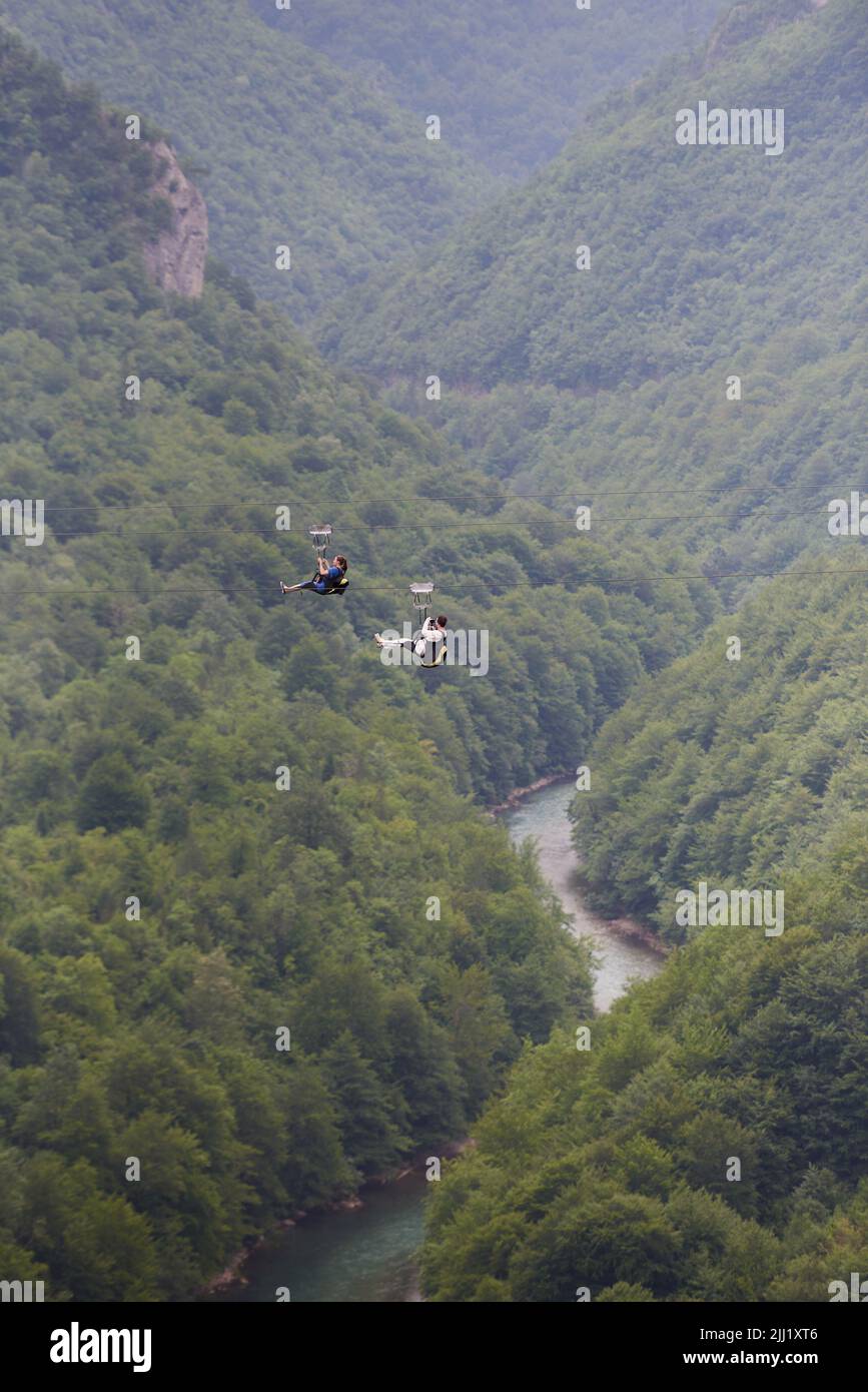 Tourists riding a zip line over the forest and lake Stock Photo - Alamy